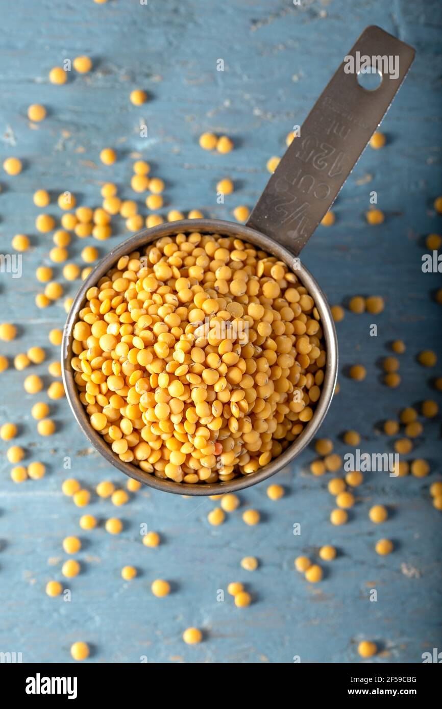 Yellow lentils in metal measuring cup on blue wooden background Stock ...