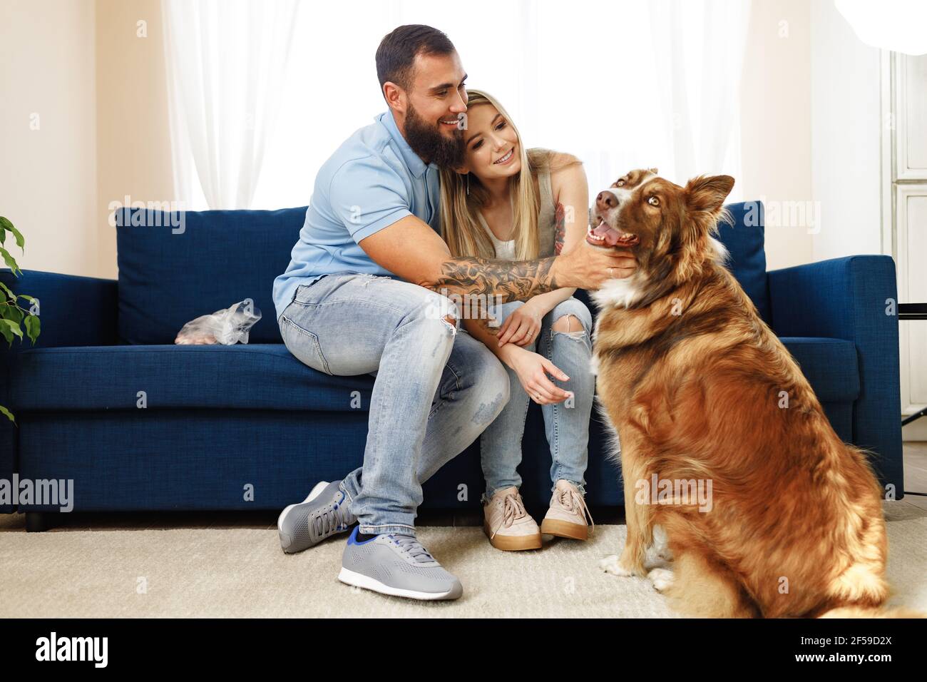 Young loving couple relaxing in living room with their dog pet Stock ...