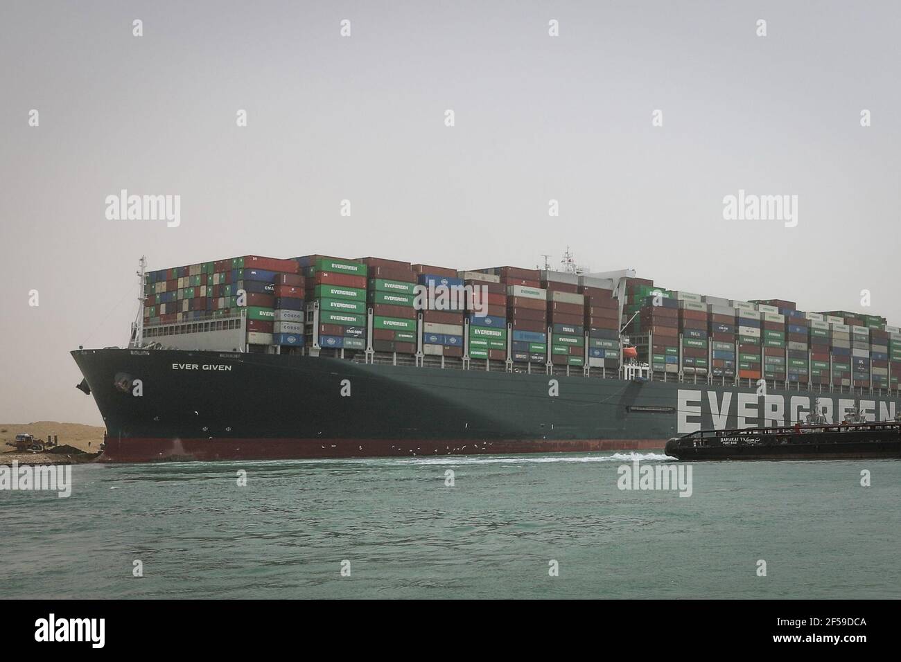 HANDOUT - 25 March 2021, Egypt, Suez: A tugboat sails past the "Ever Given", a container ship ...