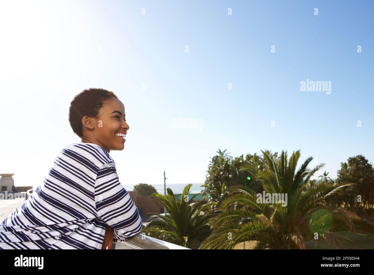 Portrait of attractive young black woman standing outside looking at ...