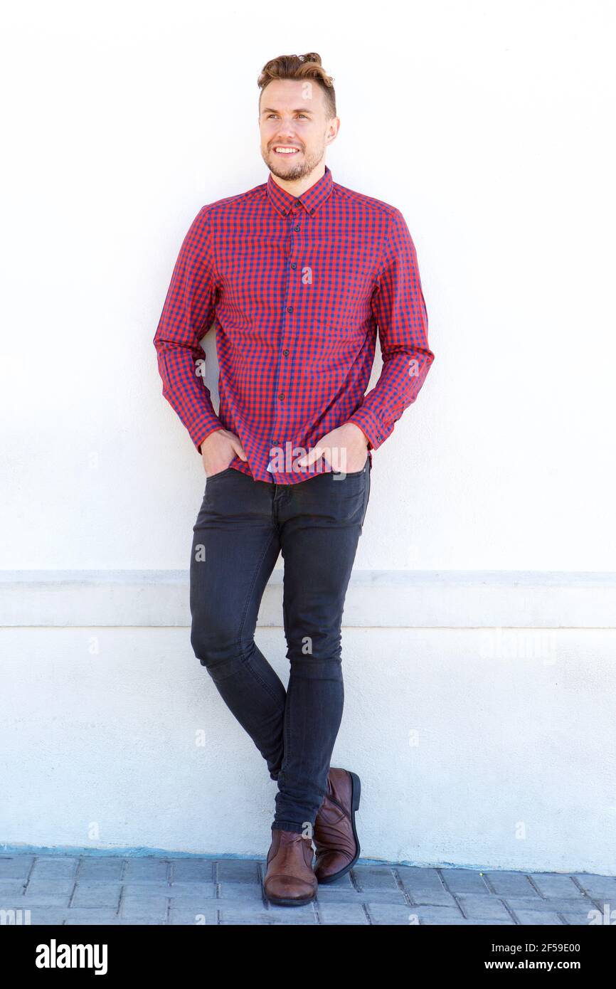 Portrait of handsome male fashion model standing against white wall ...