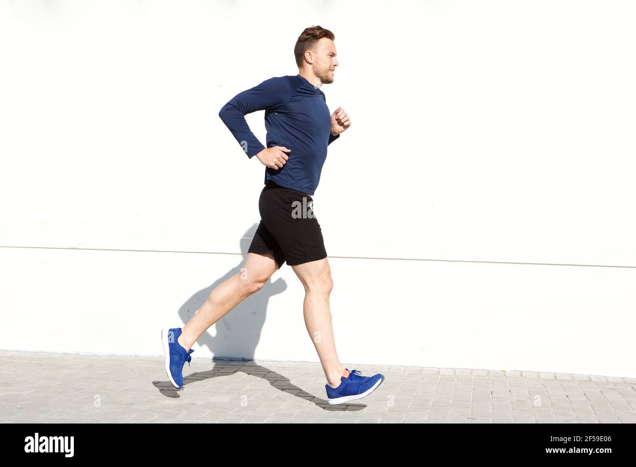 Side portrait of happy man running outside against white wall Stock ...