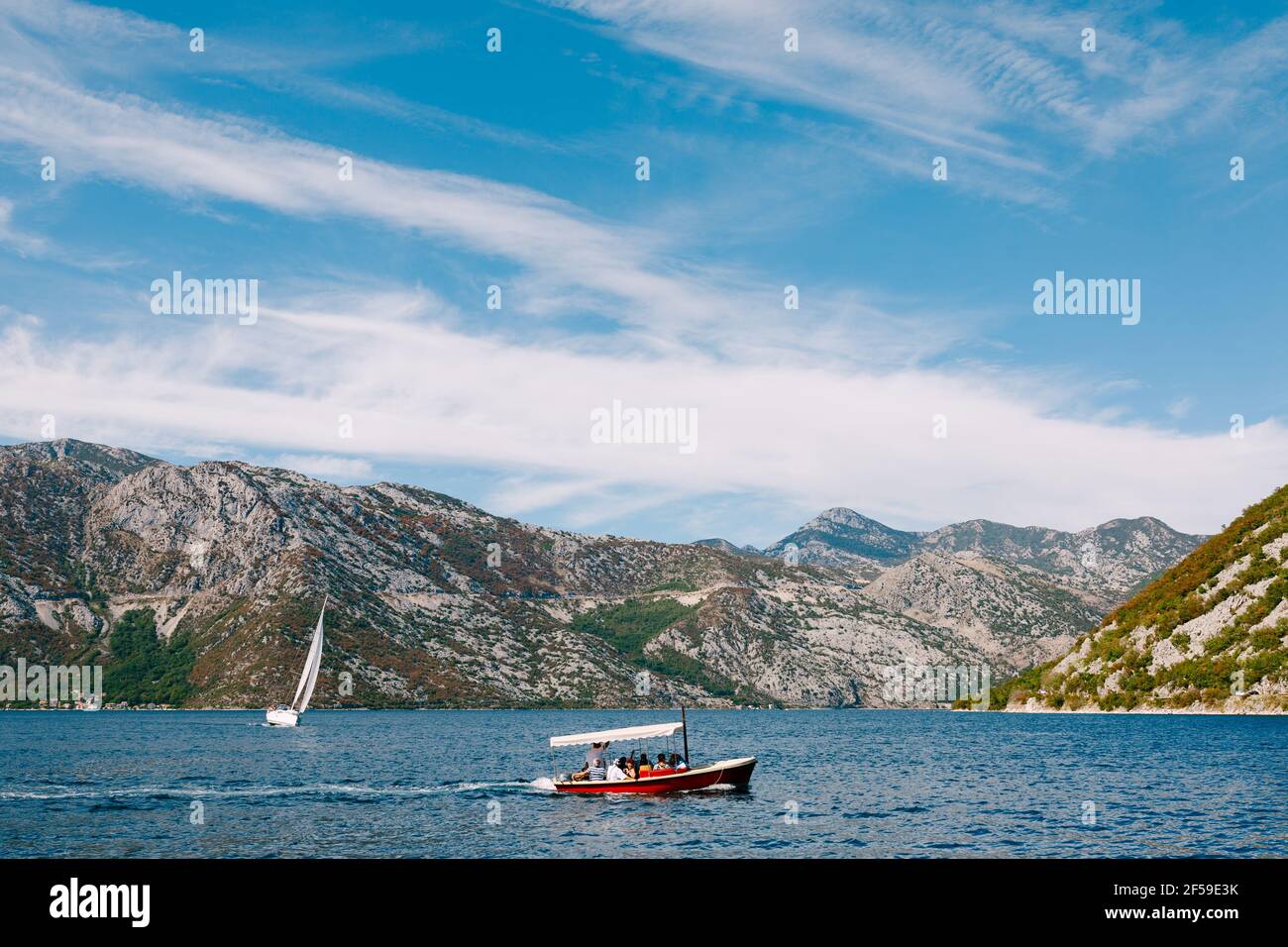 A pleasure red motor boat with an awning from the sun sails with people ...