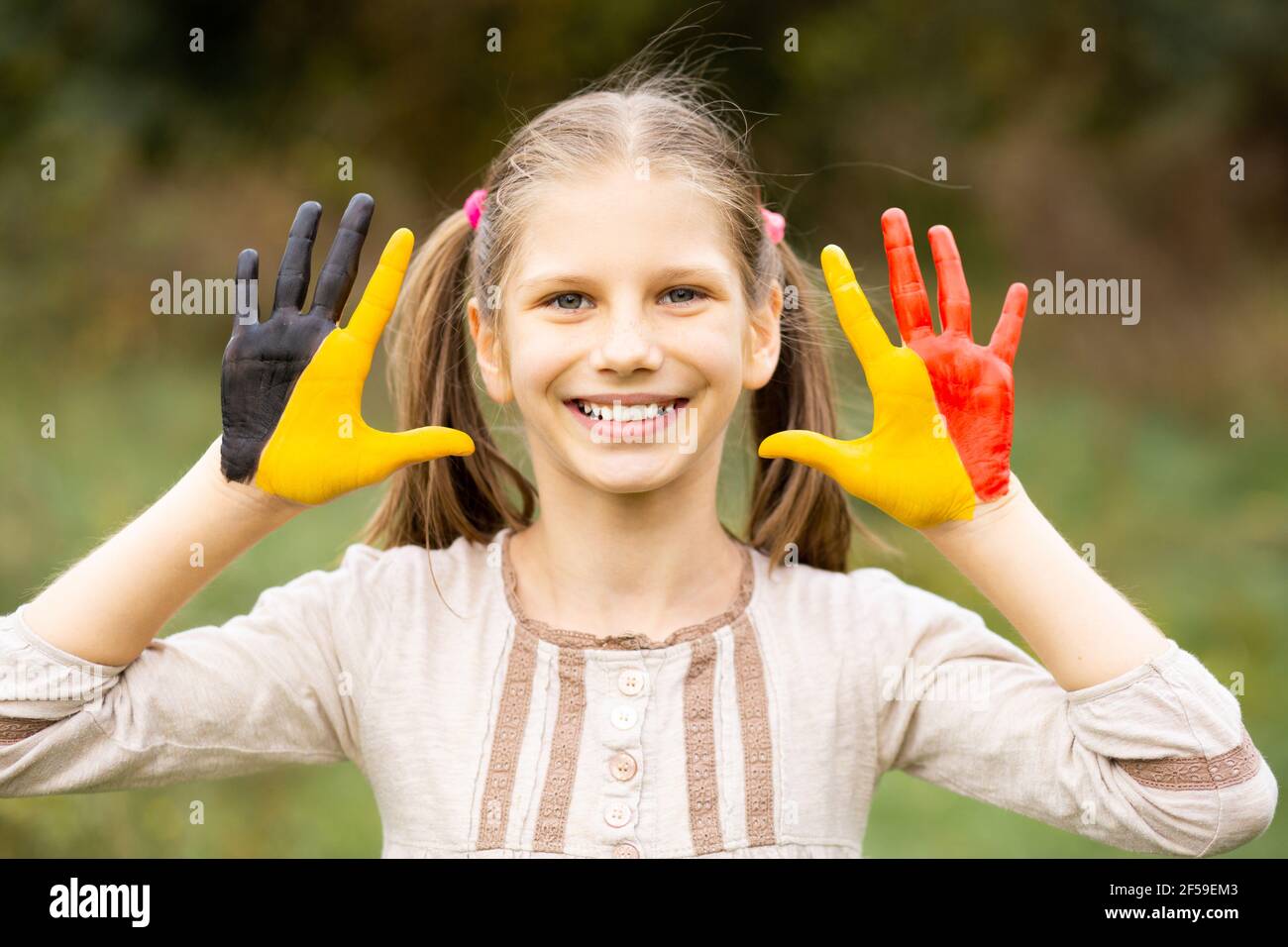 Happy outdoor portrait of child girl with hands painted in Belgium flag ...