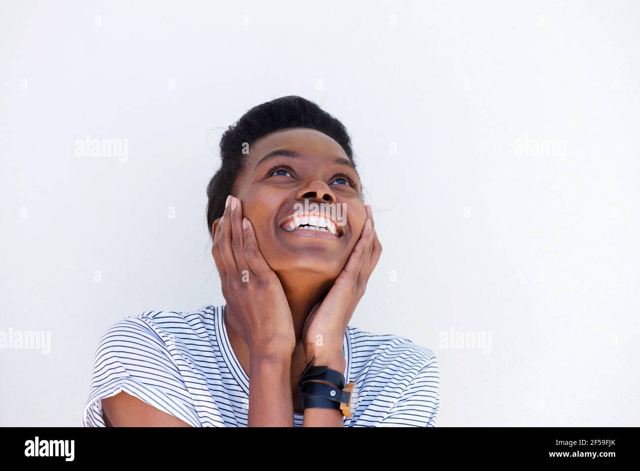 Close up portrait of young woman laughing with hands on face against ...