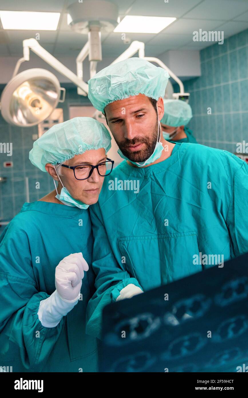 Team of surgeon doctors looking at x-ray film before surgery to set up ...