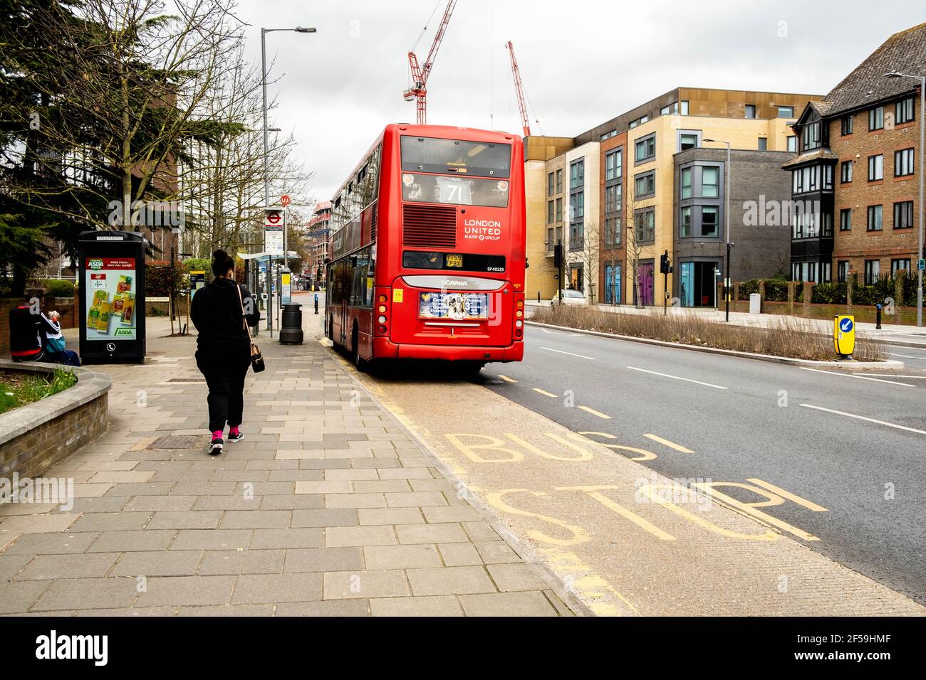 London UK, March 25 2021, Woman Alone Walking Past A Red Double Decker ...