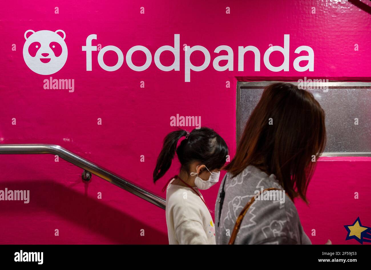 Pedestrians walk past a street commercial advertisement of the delivery ...