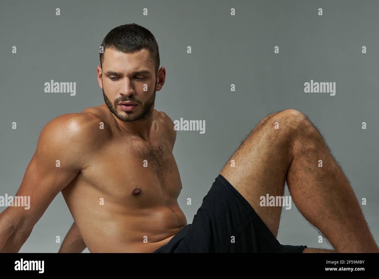 Strong adorable athlete resting after hard practice isolated on grey ...