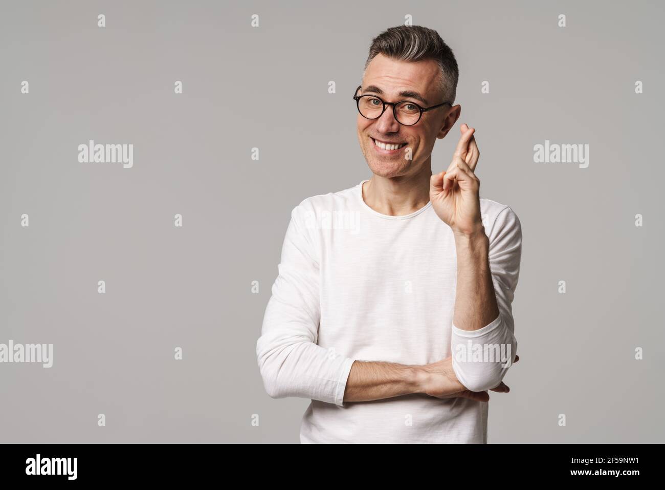 Worried smiling casual man making a wish isolated on gray background ...