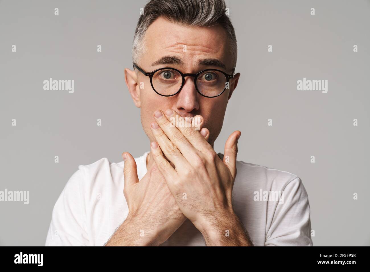 Shocked confused man in casual wear standing isolated over gray ...