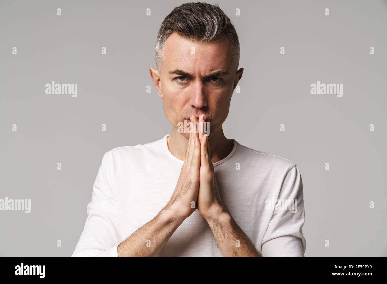 Worried man begging and praying with hands together with hope isolated ...