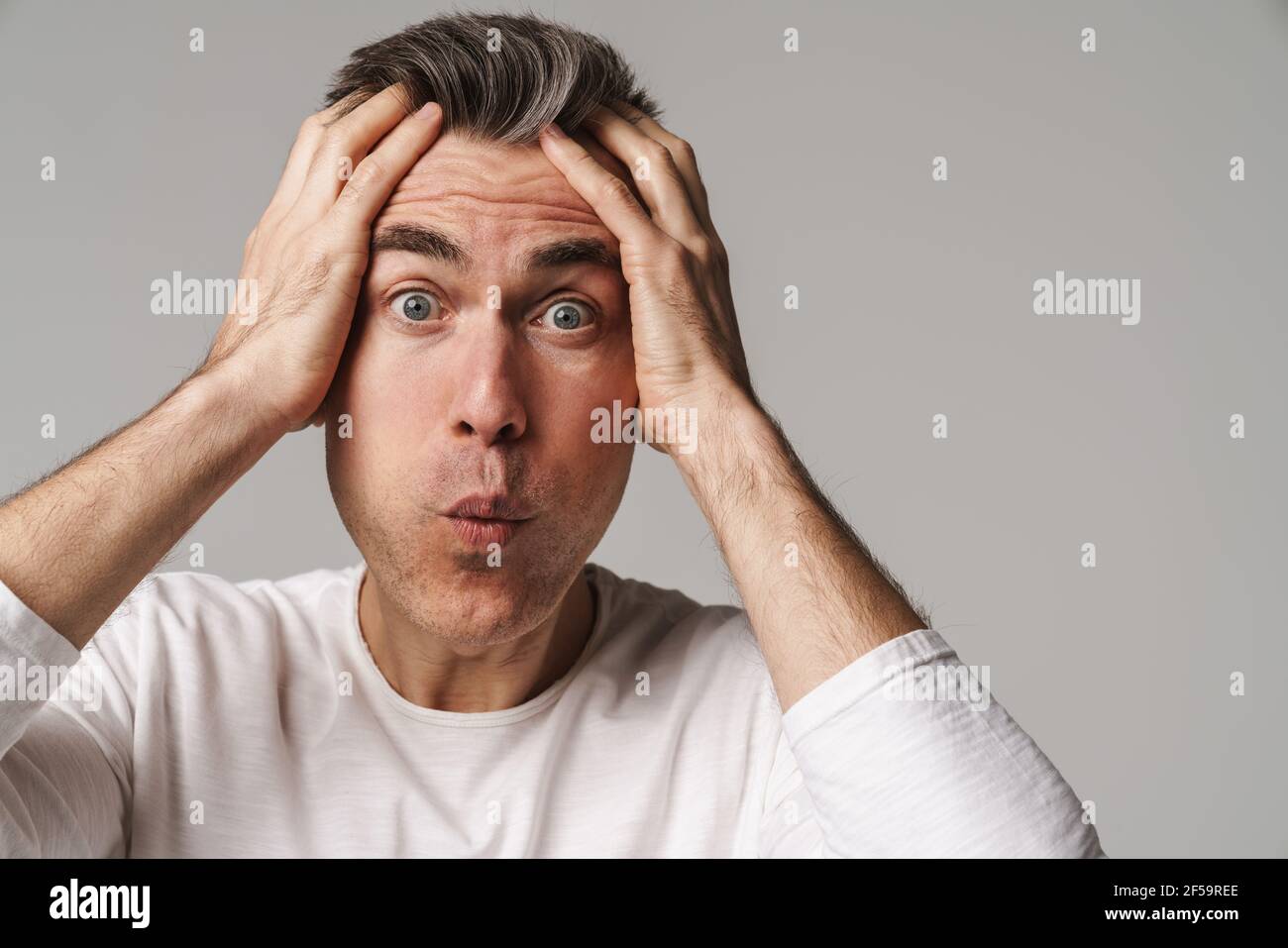 Shocked confused man in casual wear standing isolated over gray ...