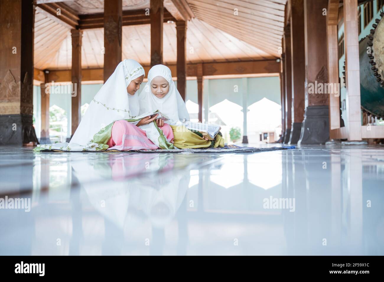 two Asian Muslim girls reading and studying the holy book of the Al ...