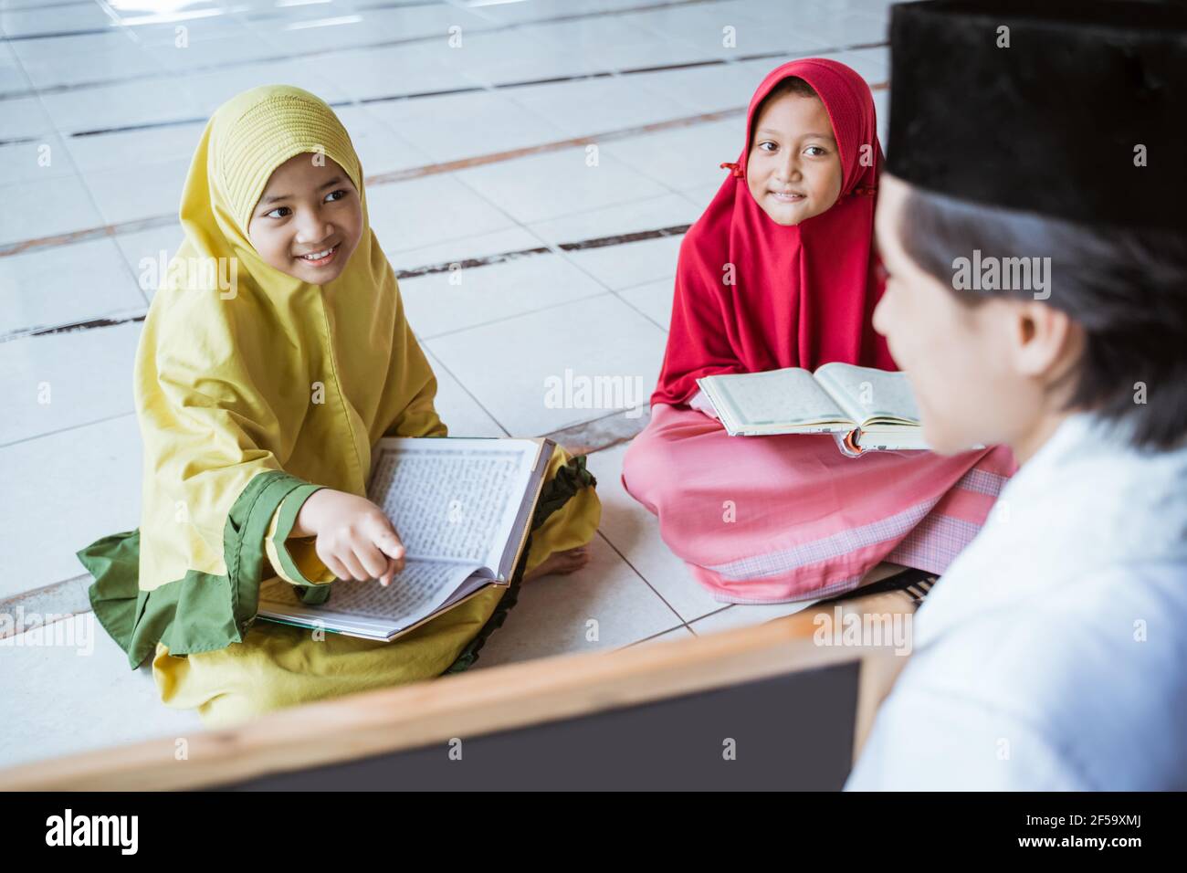 two kids learning to read quran and point to black board with muslim ...