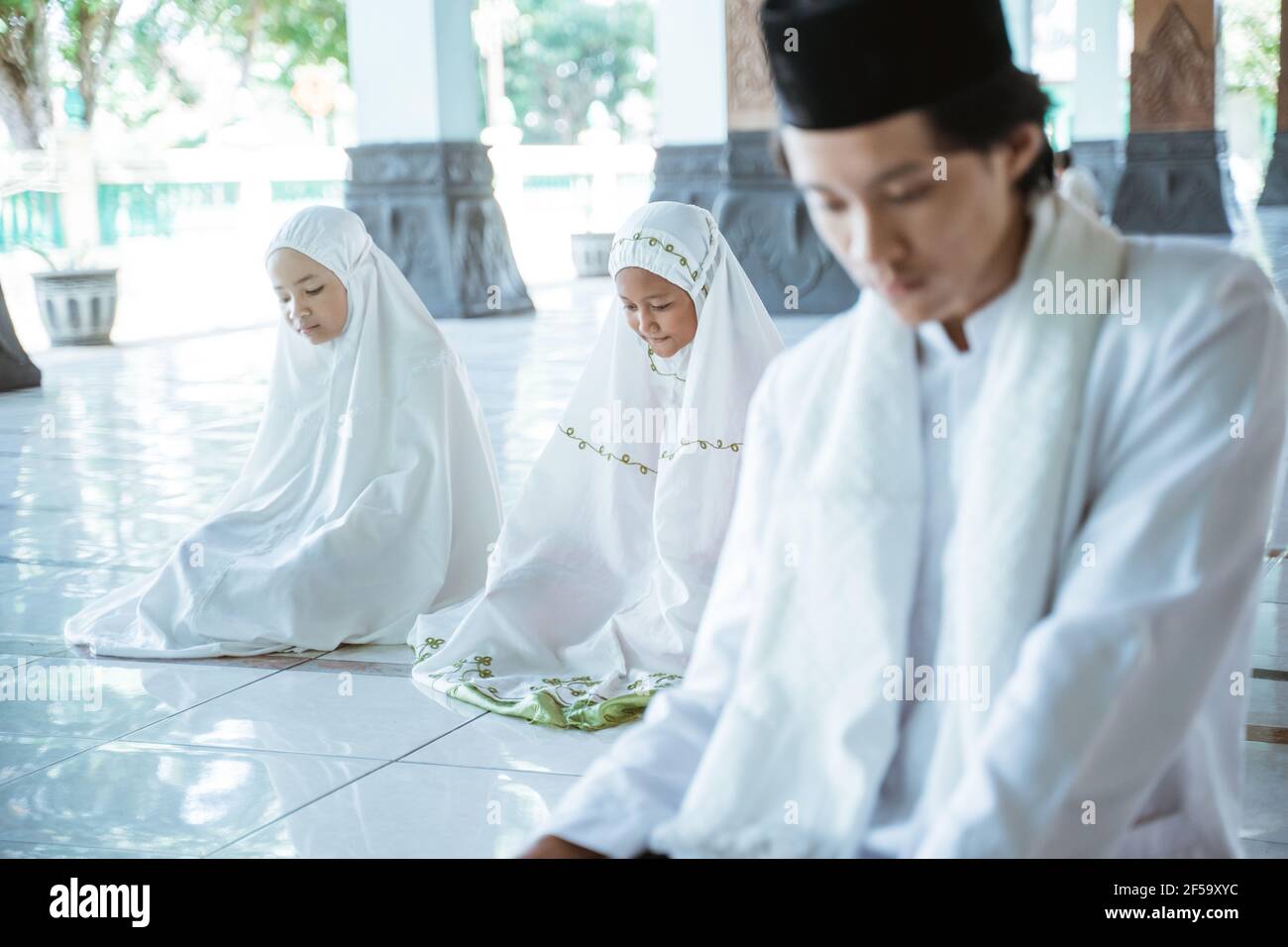 Asian Muslim male teacher and two girls praying jamaah together Stock ...