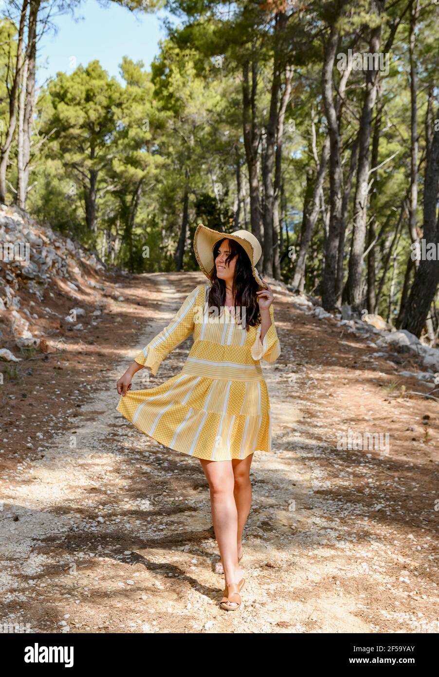 Young Croatian woman in a dress and hat walking in the park during a ...