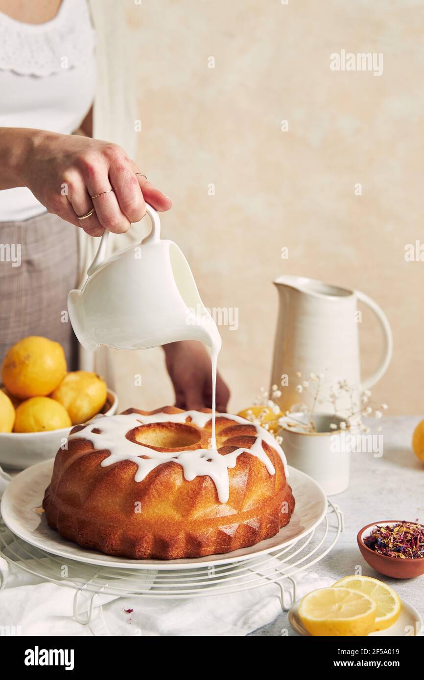 Female serving a delicious citron cake with glaze on top on a white ...