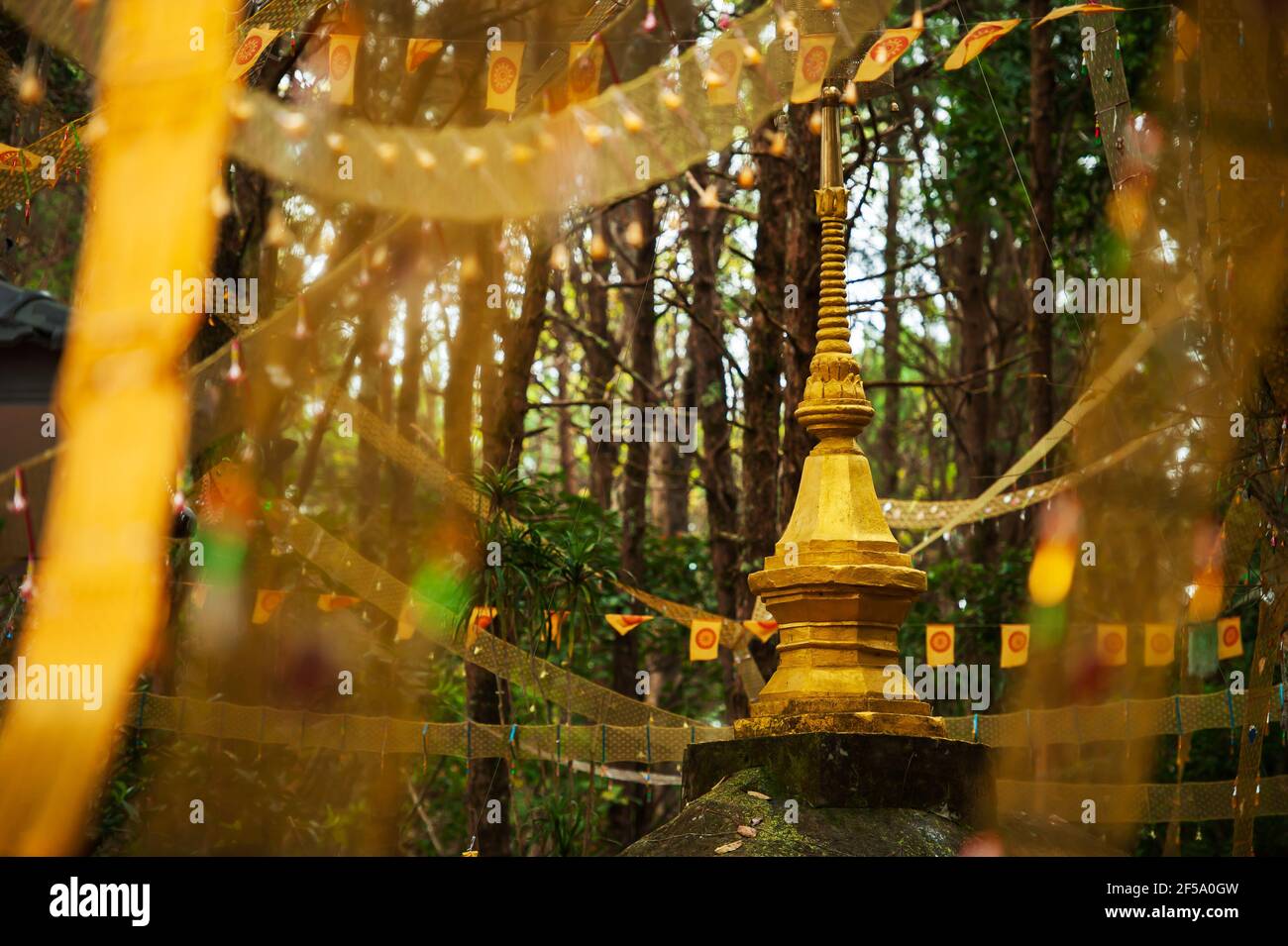 Golden pagoda and Dharmacakra flags in a deep forest, symbol of ...