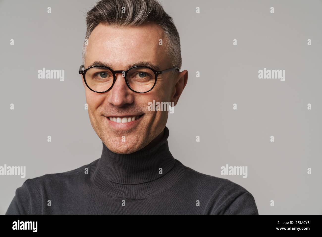 Handsome smiling confident smart looking man posing isolated over gray ...