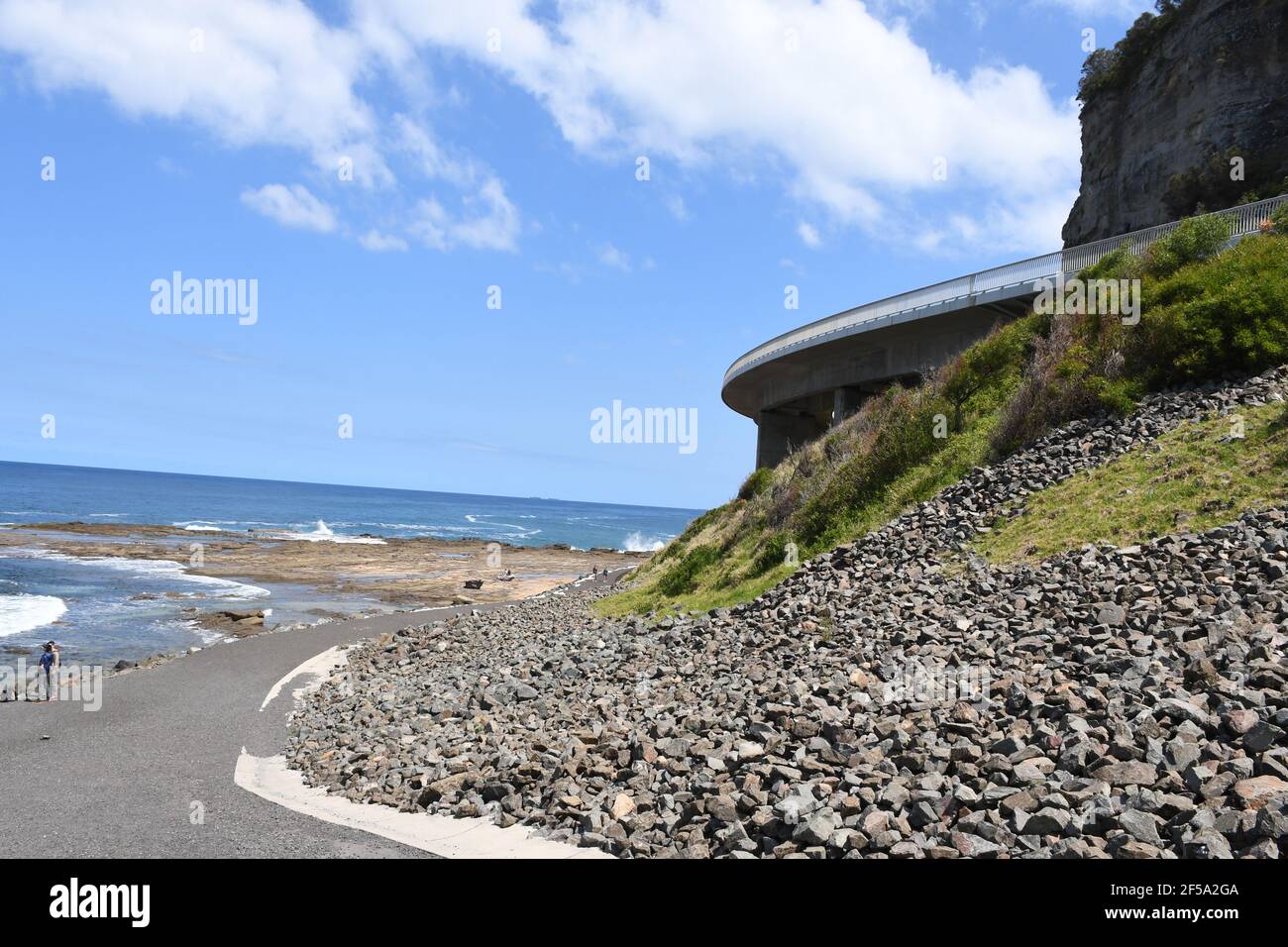 Beautiful pathway leading to the wavy ocean under the cloudy blue sky ...