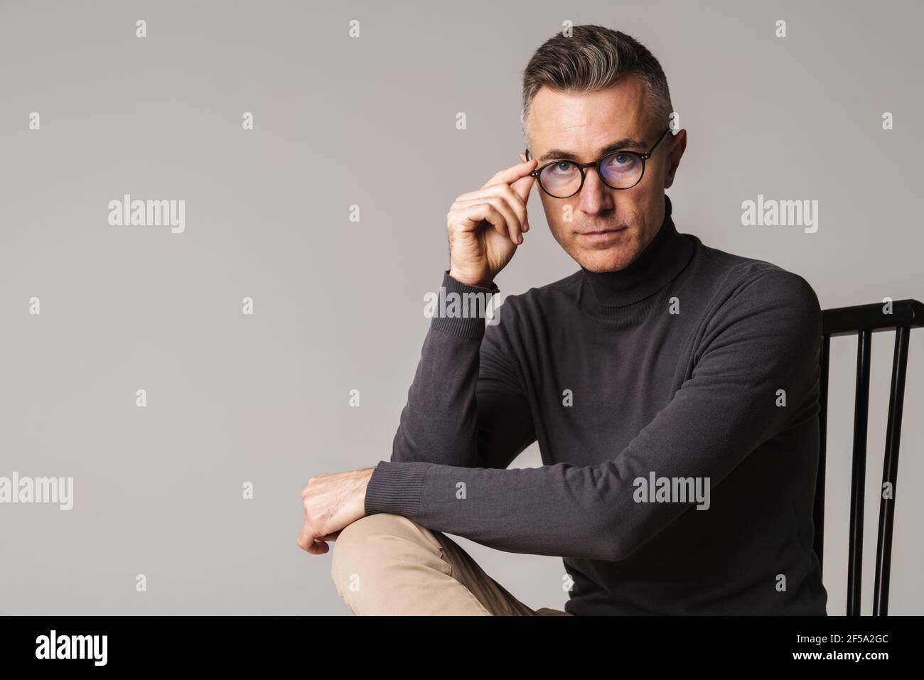 Handsome confident smart looking man sitting on a chair, posing ...