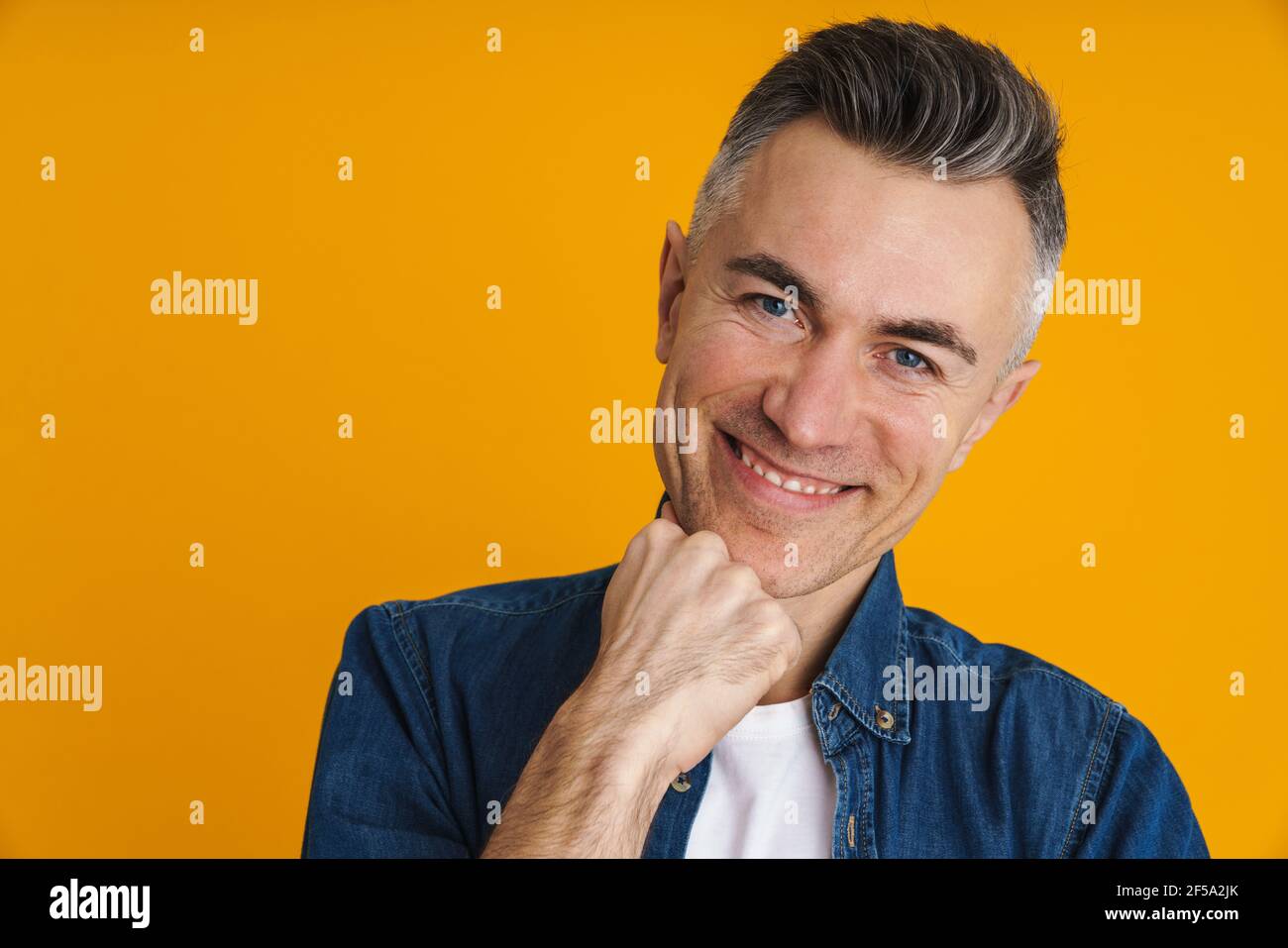 Joyful handsome man smiling and looking at camera isolated over yellow ...