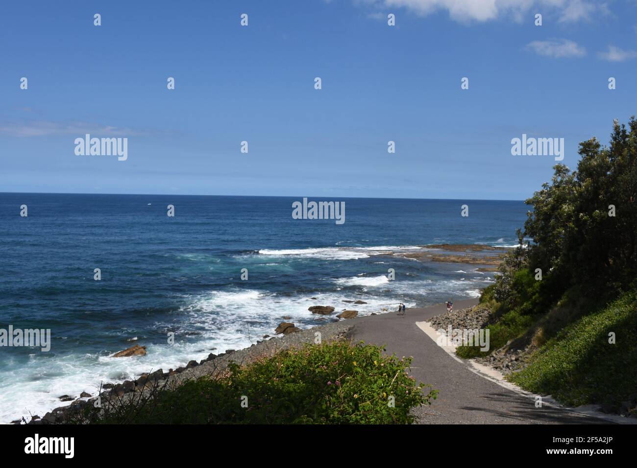 Pathway leading to the wavy sea gleaming under the blue sky on the ...