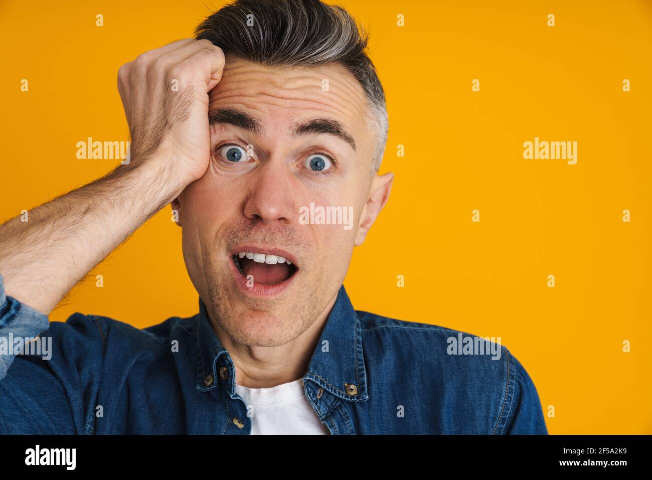 Excited handsome man expressing surprise on camera isolated over yellow ...