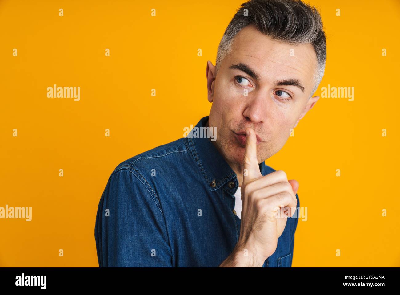 Serious handsome man showing silence gesture at camera isolated over ...