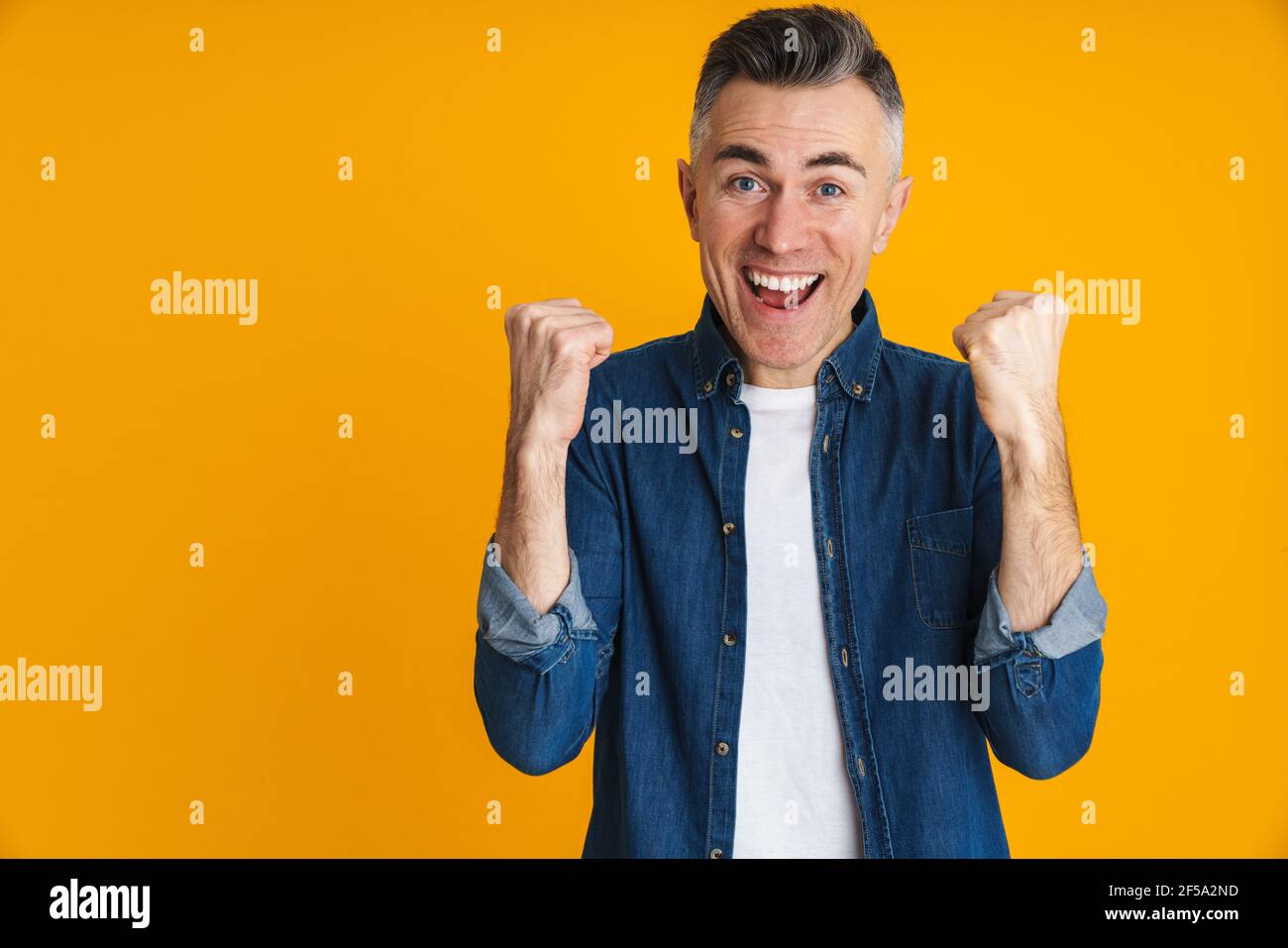 Excited handsome man exclaiming and showing winner gesture isolated ...