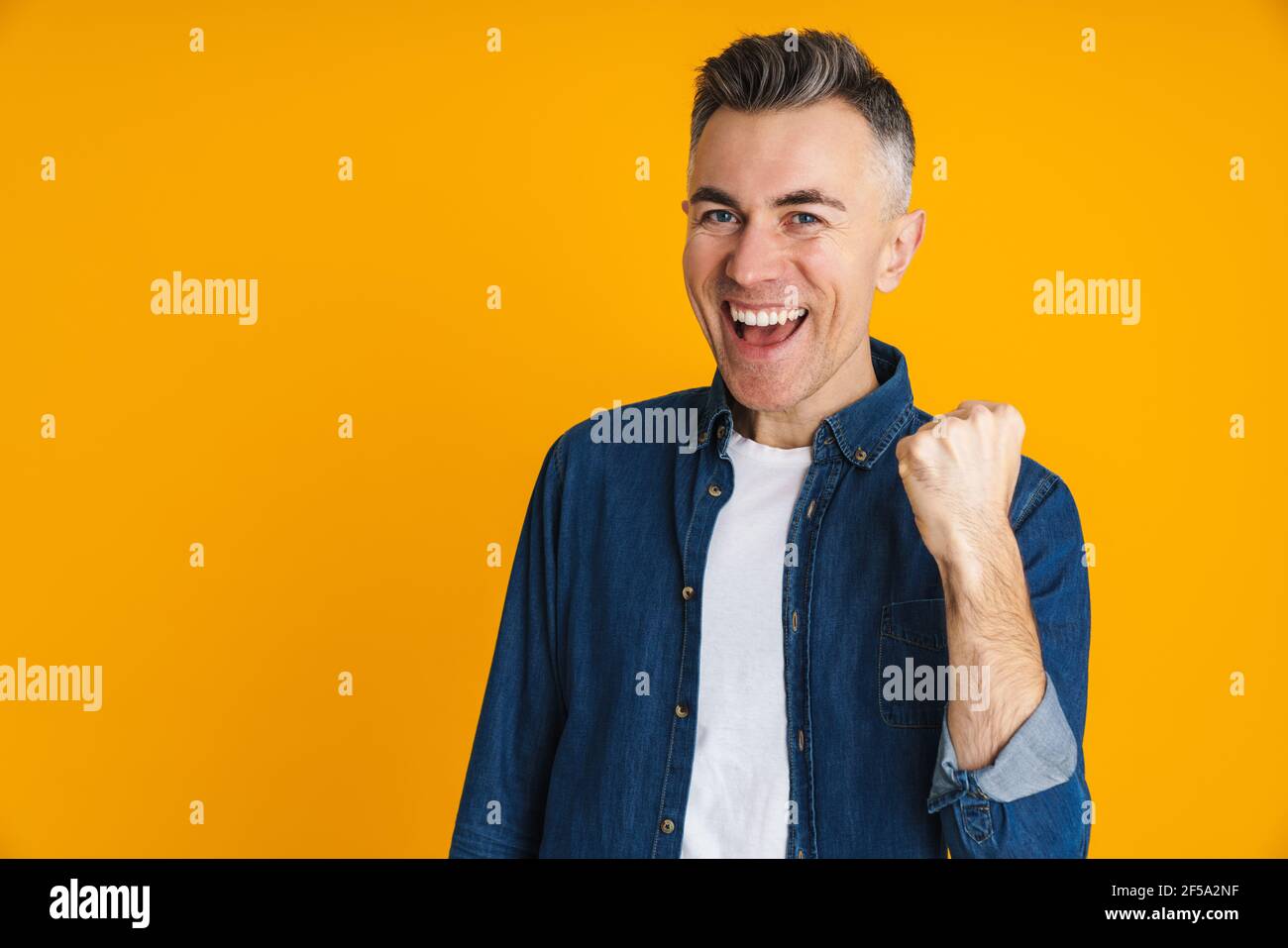 Excited handsome man exclaiming and showing winner gesture isolated ...