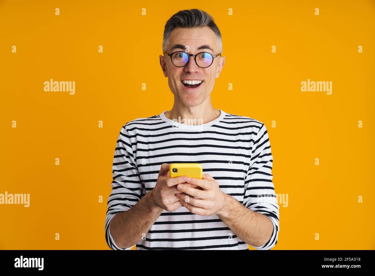 Excited handsome man exclaiming while using cellphone isolated over ...