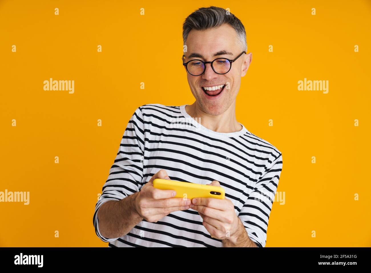 Delighted handsome man playing online game on mobile phone isolated ...