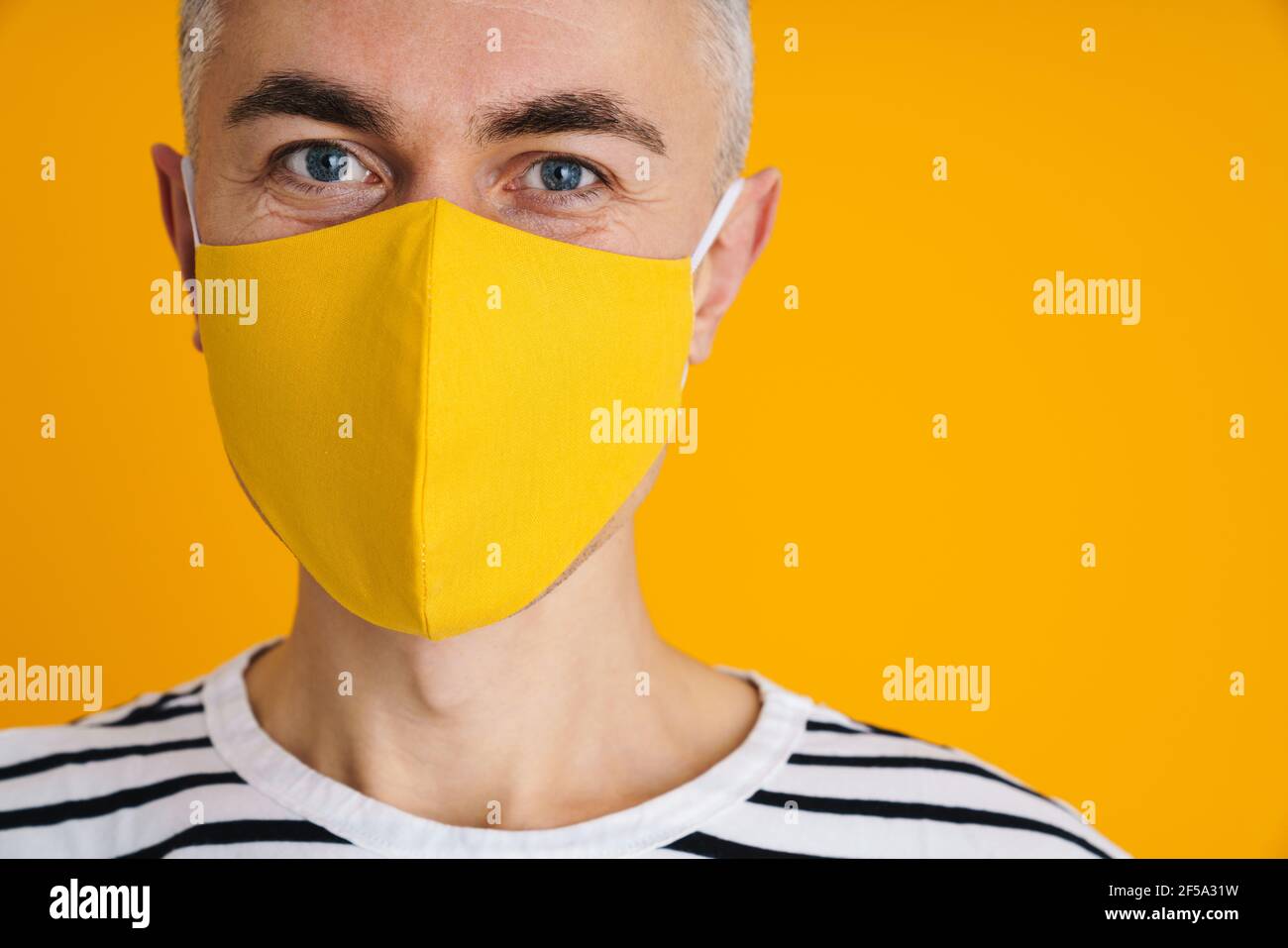 Joyful handsome man in protective mask looking at camera isolated over ...