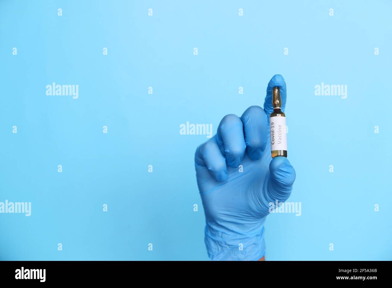 hand in latex gloves holding glass ampoule vaccine, with copy space ...
