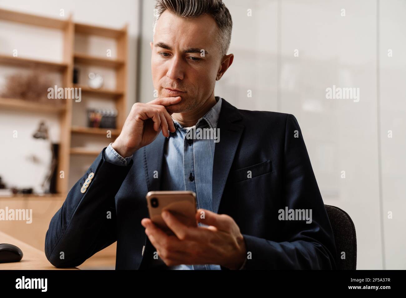 Focused grey man using mobile phone while working in office Stock Photo ...