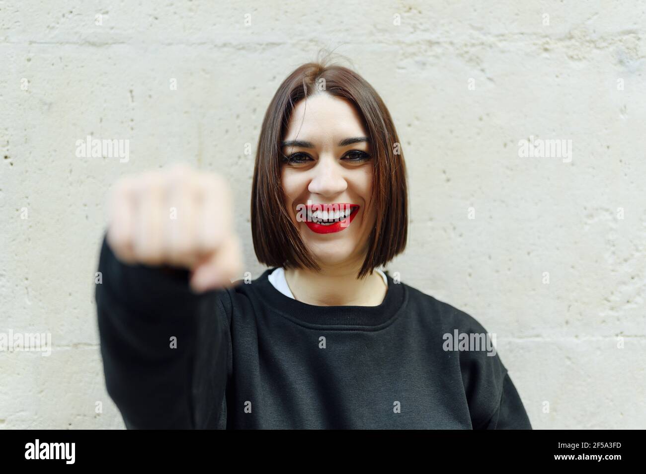 Cheerful Spanish female has stretched her fist forward as a symbol of ...