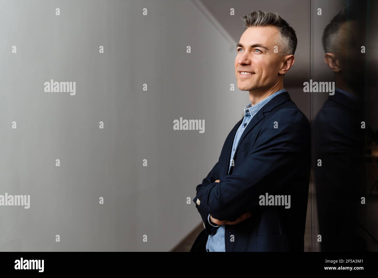 Happy grey man smiling and looking upward while leaning on wall in ...