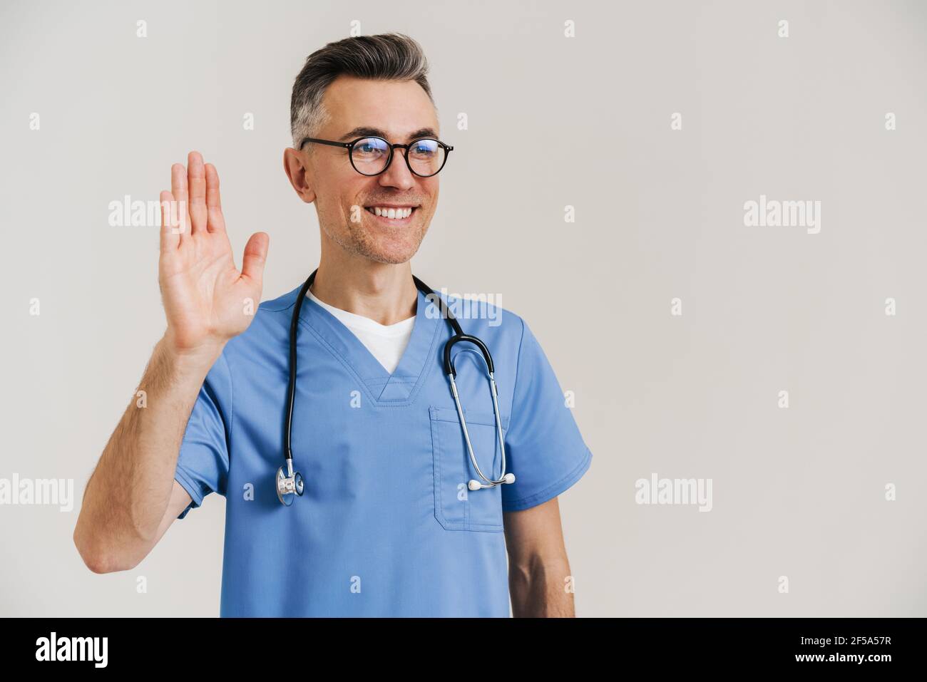 Happy white-haired medical doctor with stethoscope smiling and waving ...