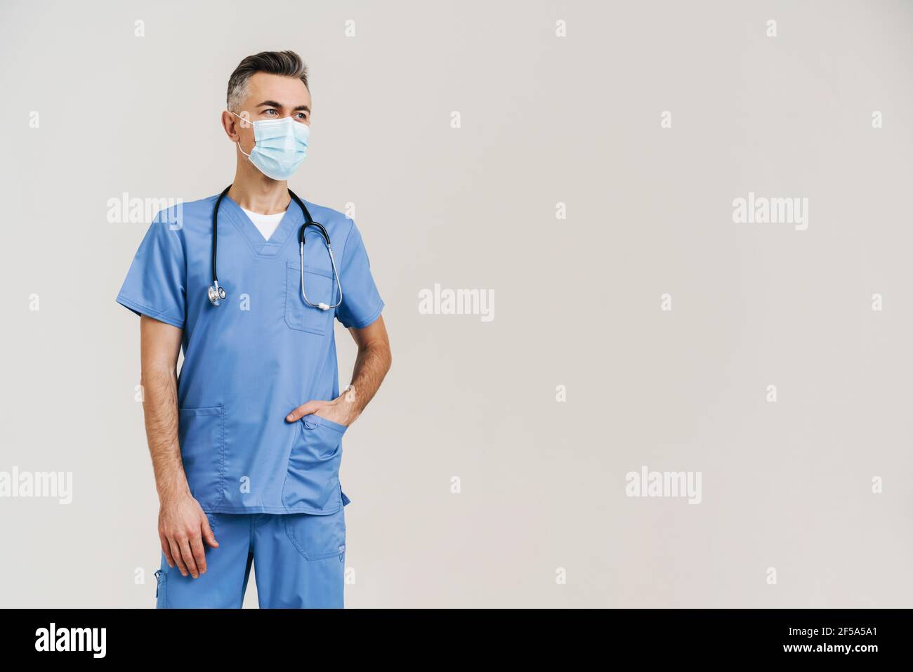 Confident white-haired medical doctor in face mask posing with ...