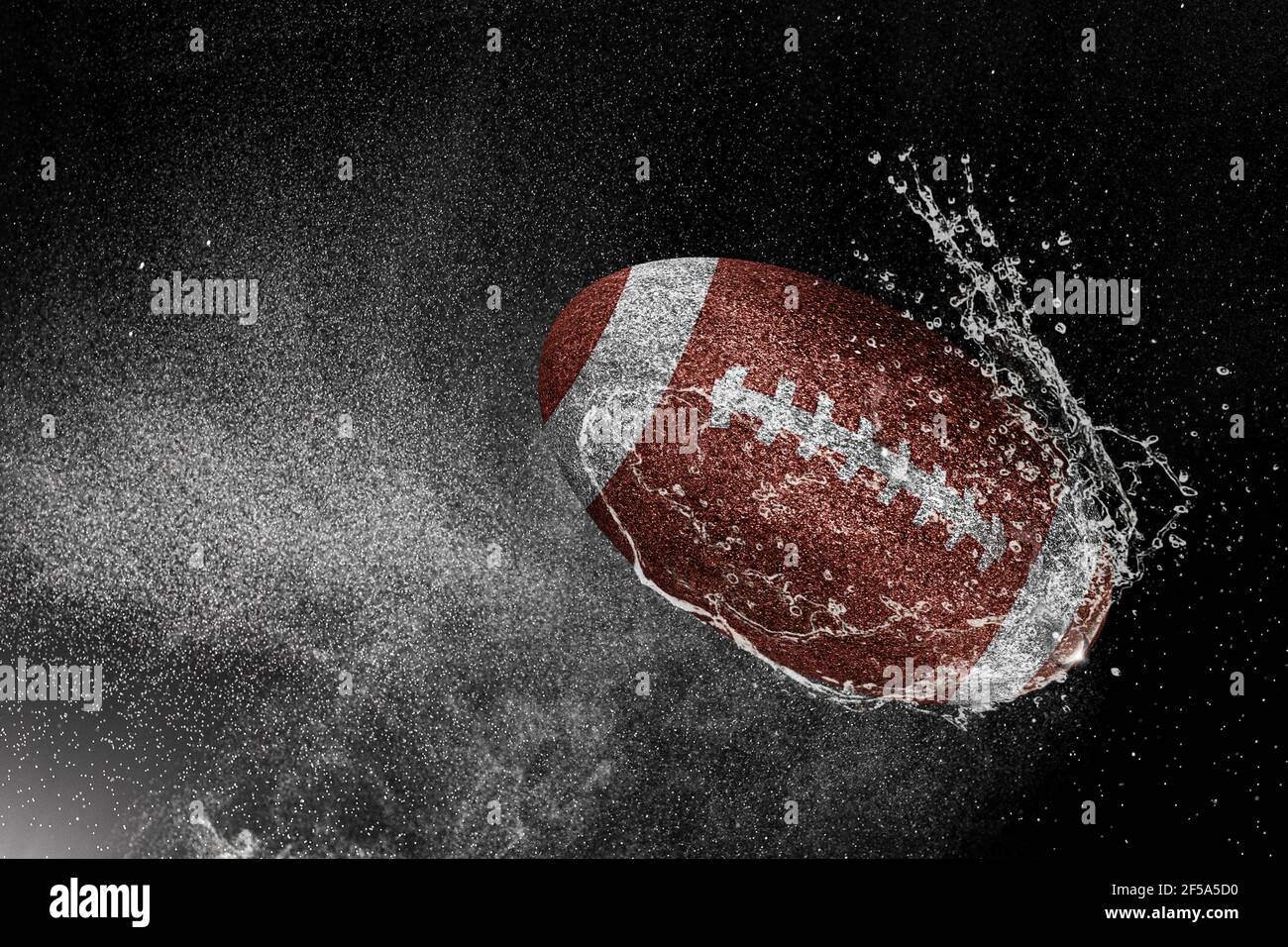 American football ball flying in water drops and splashes isolated on ...