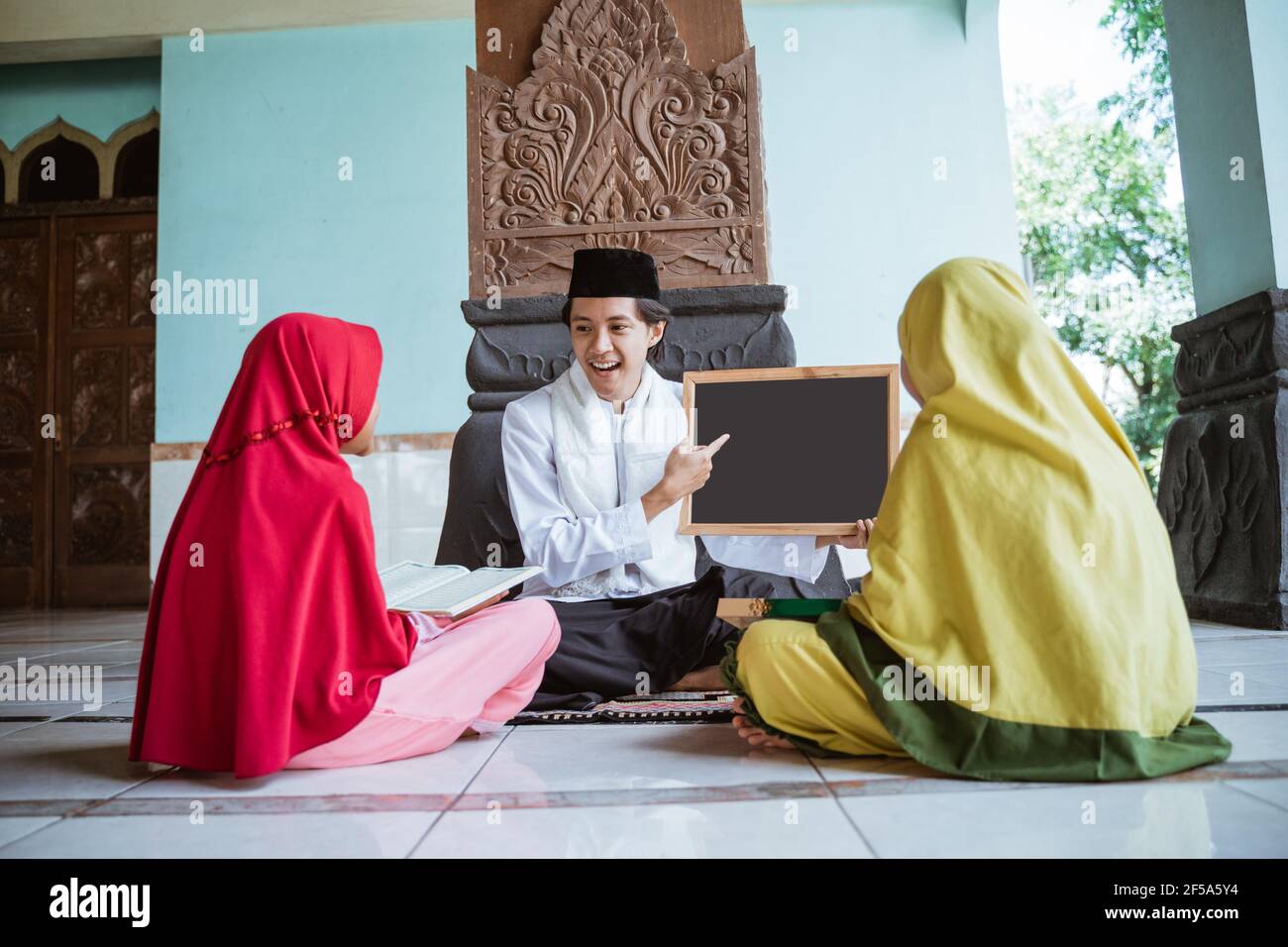 muslim man teacher hold pointing black board and teach two kids muslim ...