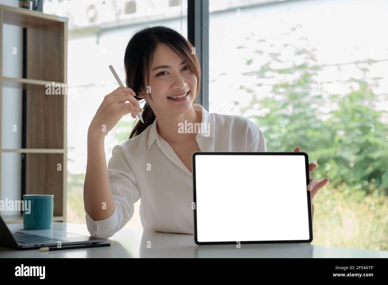 Business woman holding and pointing at digital tablet with blank screen ...