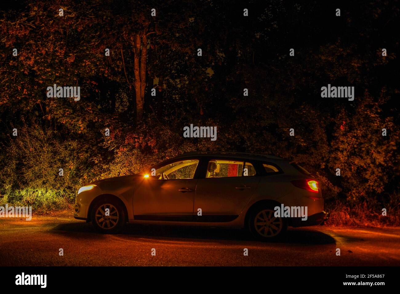 Side view of a modern empty car standing in the dark with external and ...