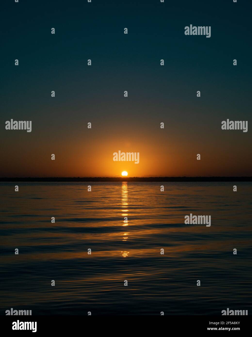 Beautiful view of the calm ocean with tiny waves during the sunset on a ...