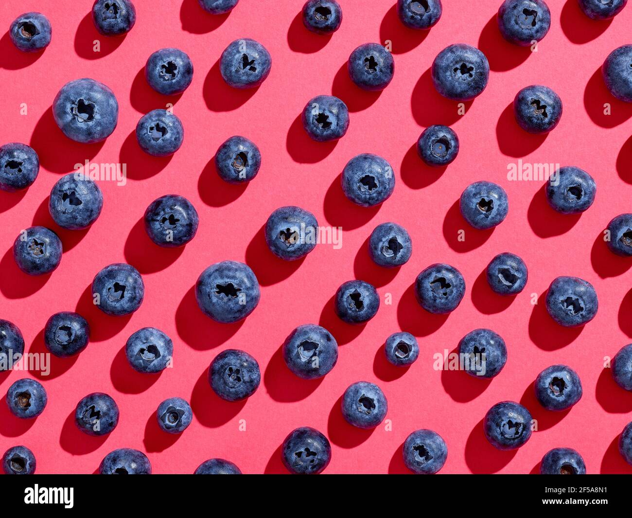 Colorful blueberry pattern on pink background, from above, hard shadow ...