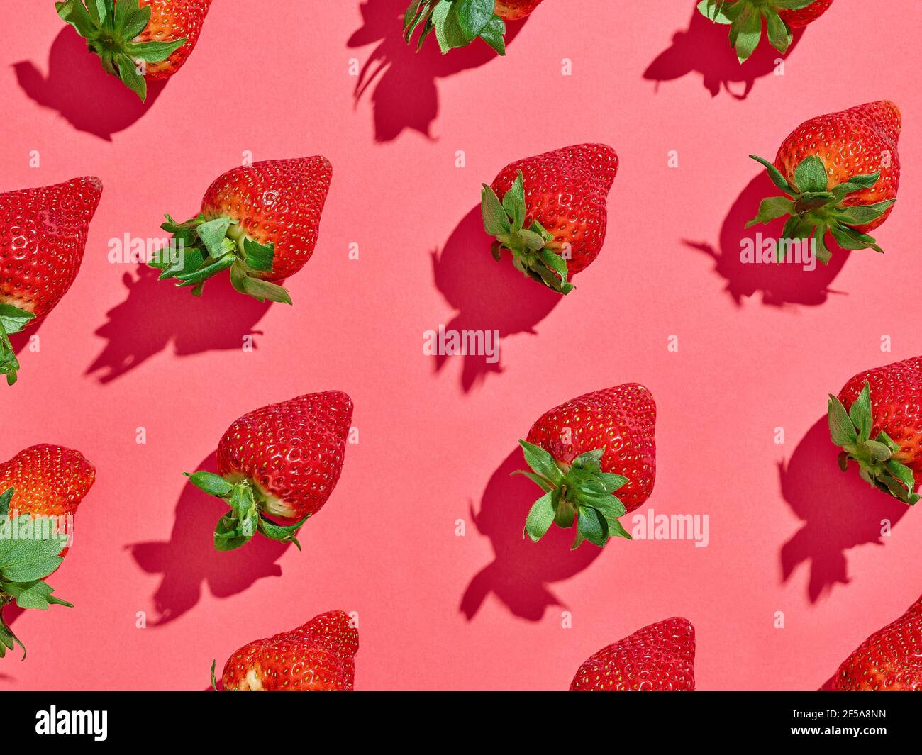 Colorful strawberry pattern on pink background, from above, hard shadow ...
