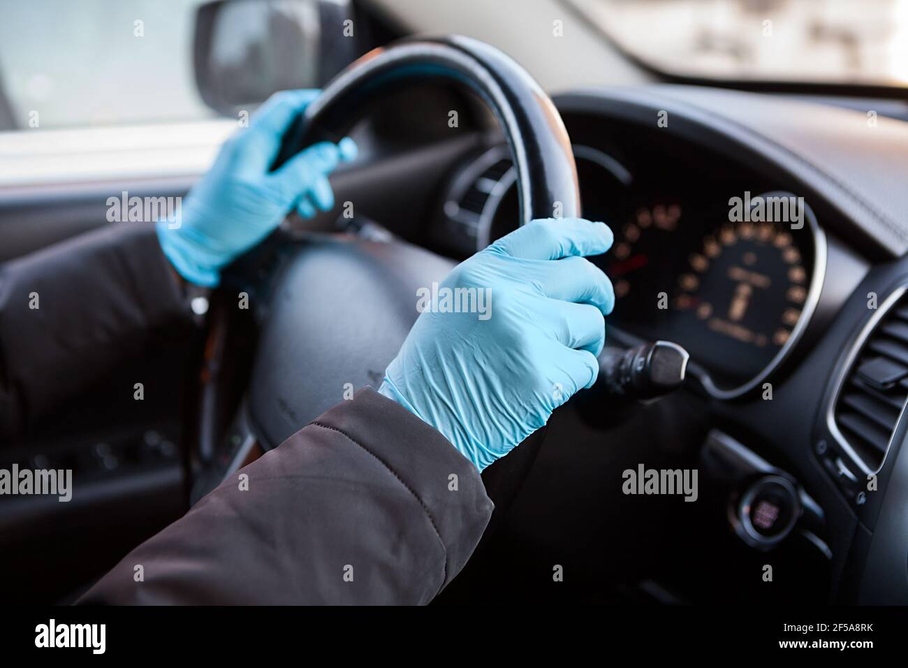 Drivers hands in blue rubber gloves holding steering wheel of car ...