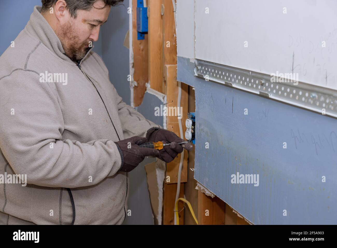 Removal and replacement old broken an electrical outlet into the wall ...